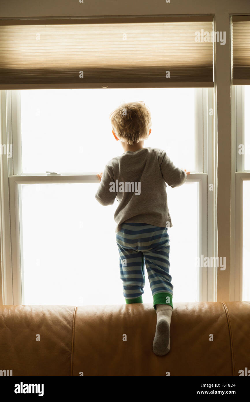 Caucasian boy looking out window Stock Photo - Alamy