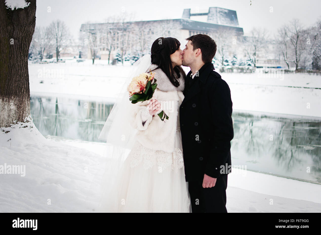 Wedding couple in winter snowly street background cold river Stock ...