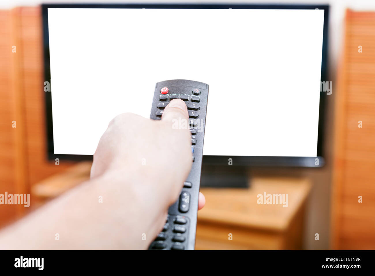 Hand turns on TV with cut out screen by remote control in living room ...