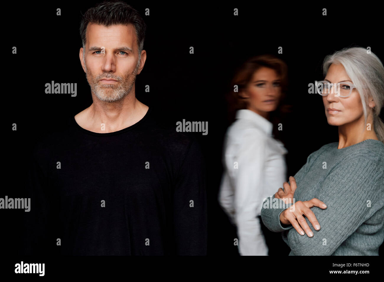 Portrait of serious looking business people in front of black ...