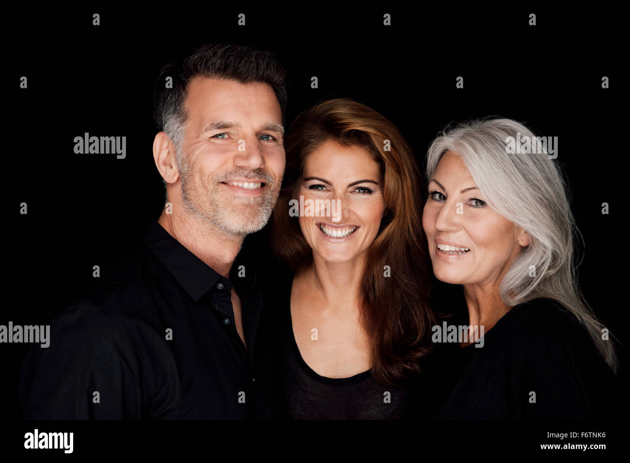Portrait of three smiling people in front of black background Stock ...