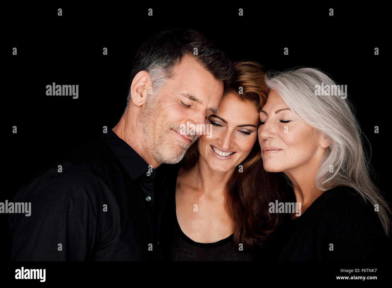 Three smiling people head to head in front of black background Stock ...