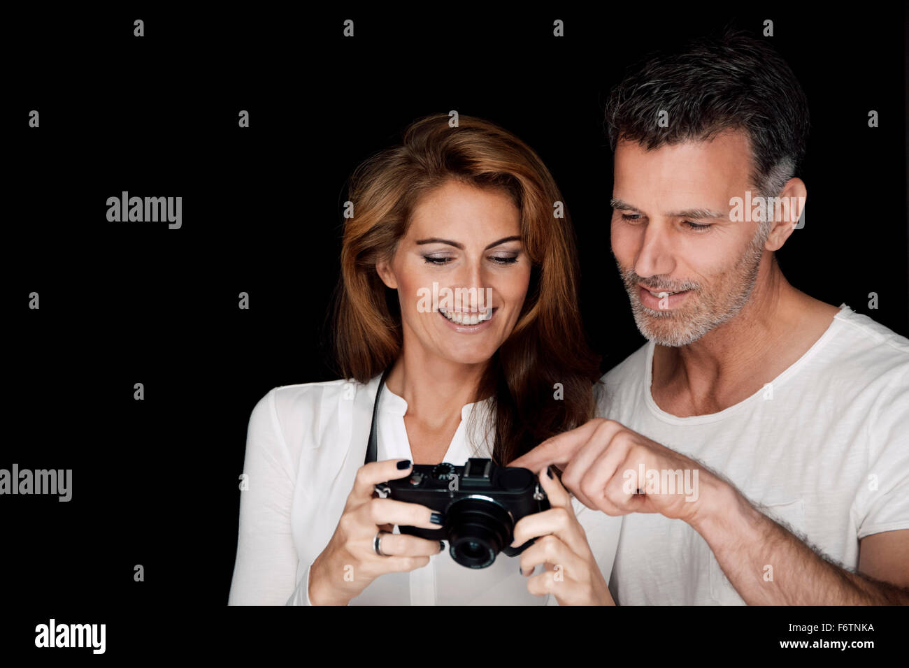 Portrait of man and woman looking at camera in front of black ...
