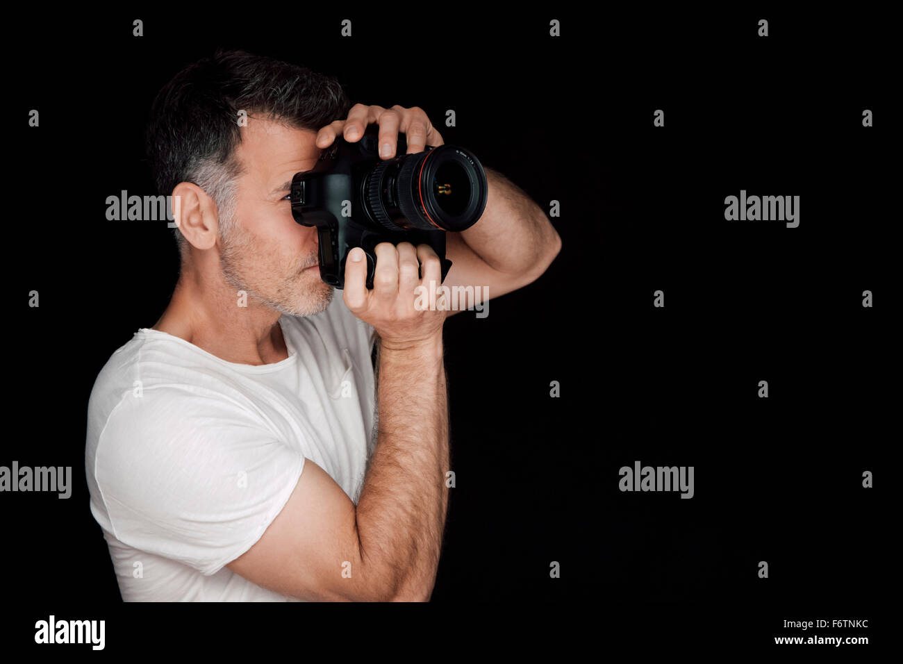 Man photographing with camera in front of black background Stock Photo ...