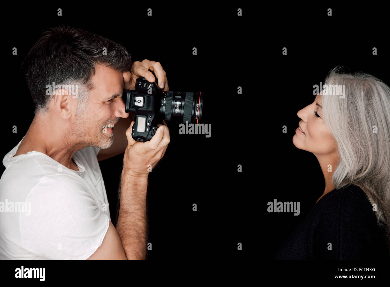 Man photographing woman in front of black background Stock Photo - Alamy