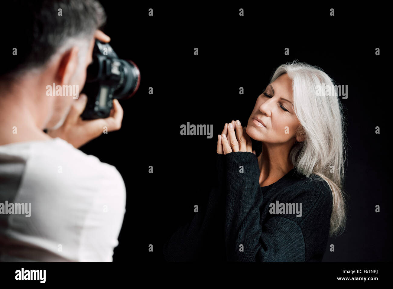 Man photographing woman in front of black background Stock Photo - Alamy
