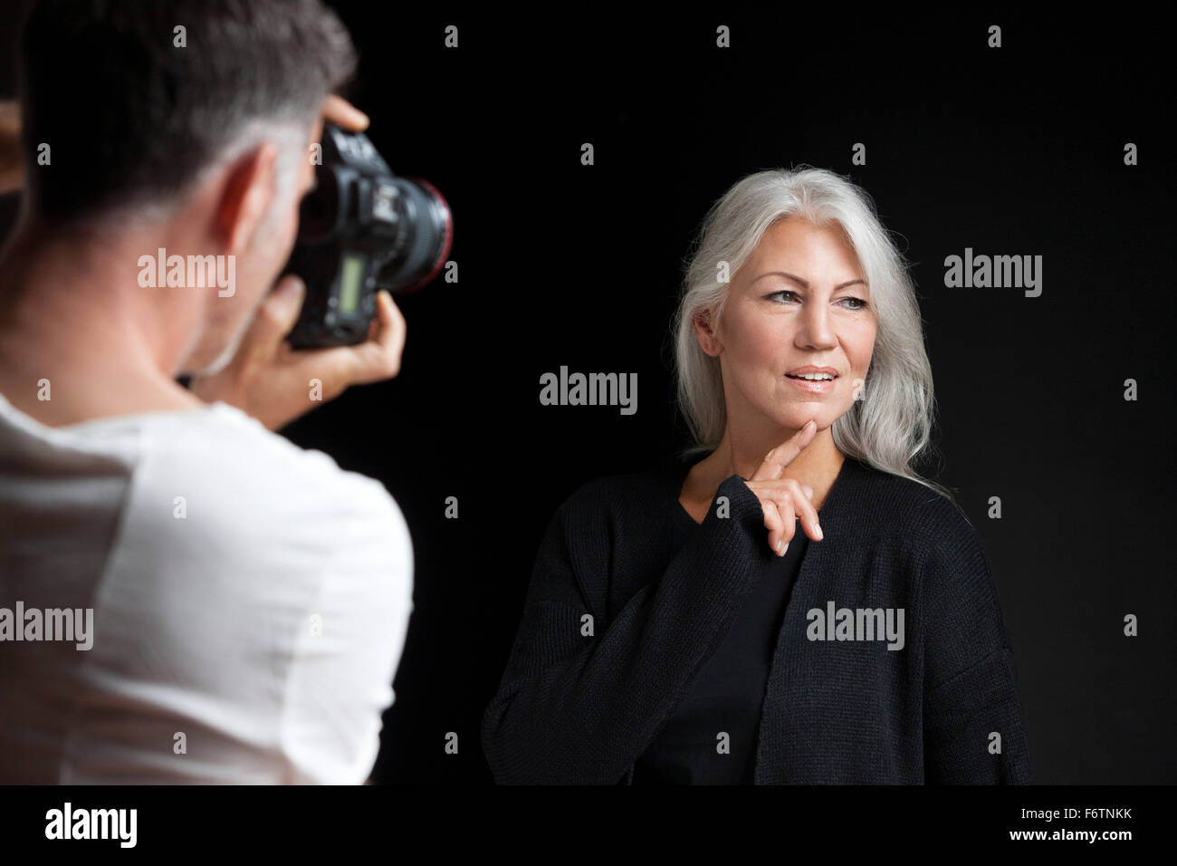 Man photographing woman in front of black background Stock Photo - Alamy