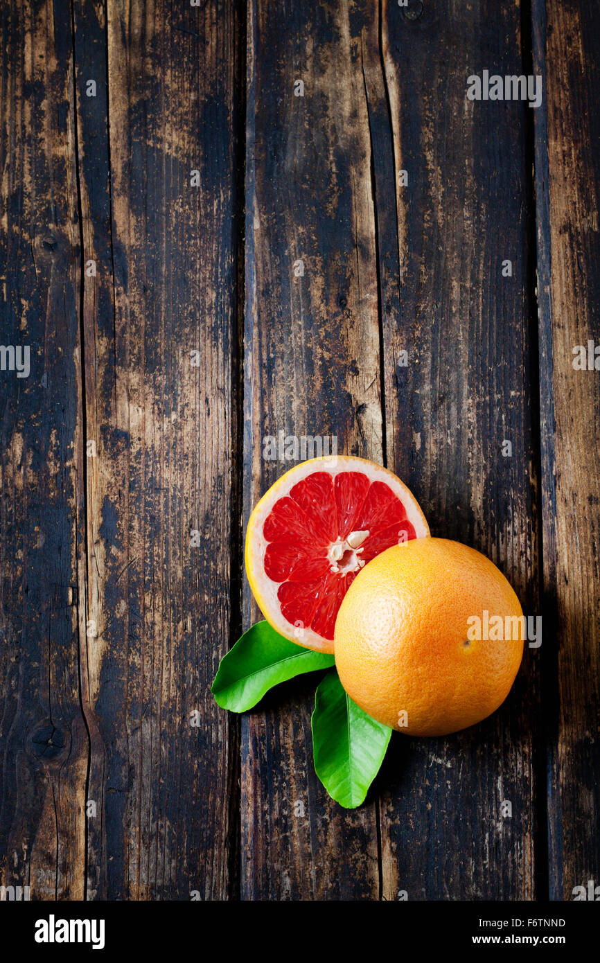 Sliced red grapefruit with leaves on dark wood Stock Photo - Alamy