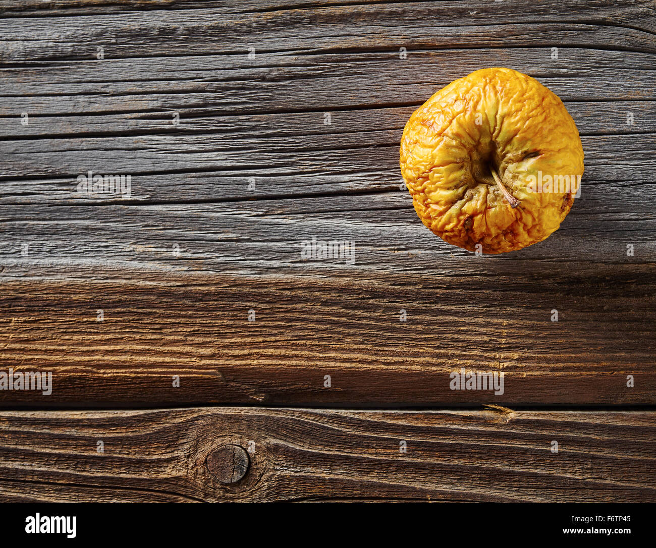 Shrivelled apple on rough wood Stock Photo - Alamy