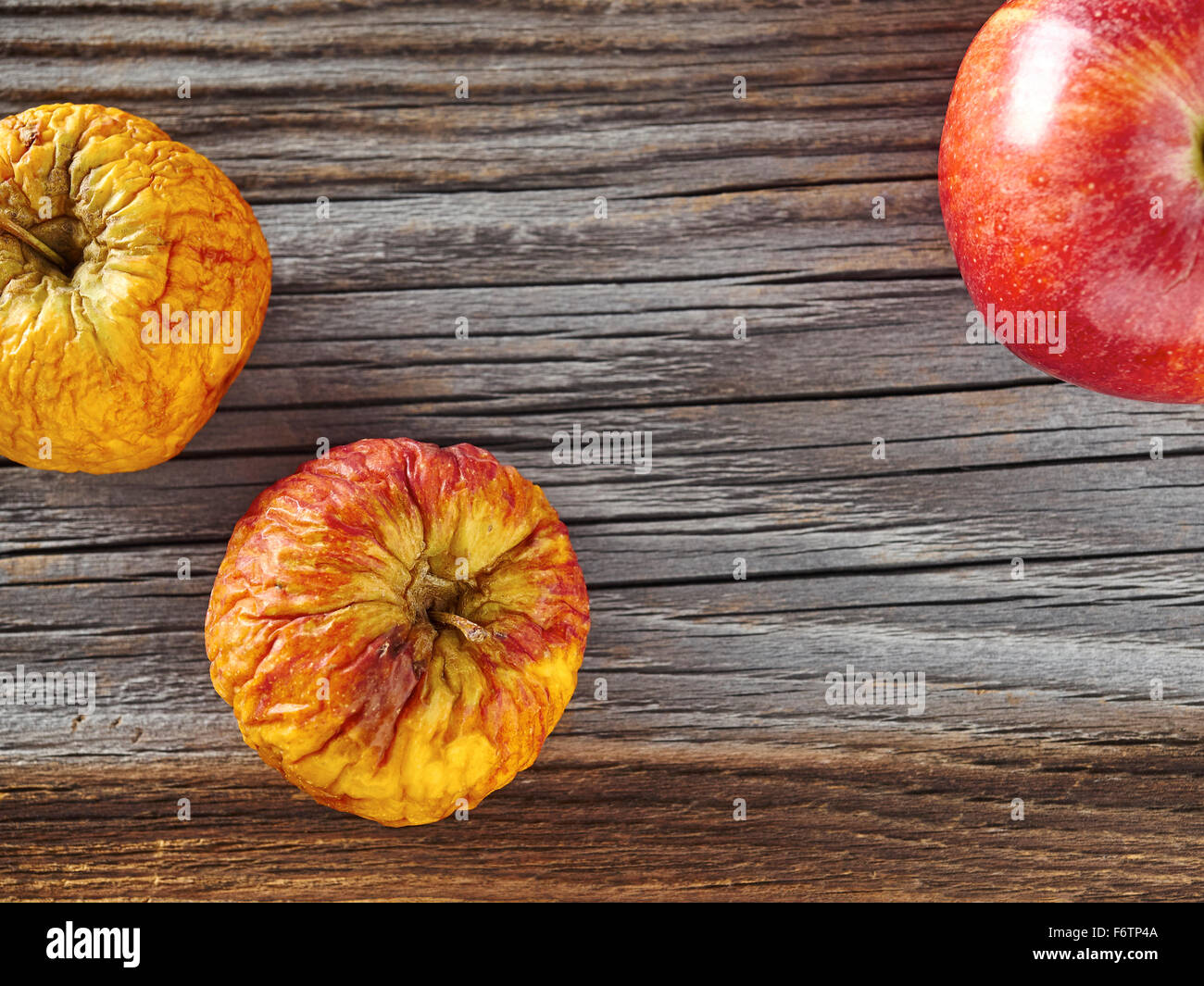 Fresh red apple and a shrivelled one on rough wood Stock Photo - Alamy