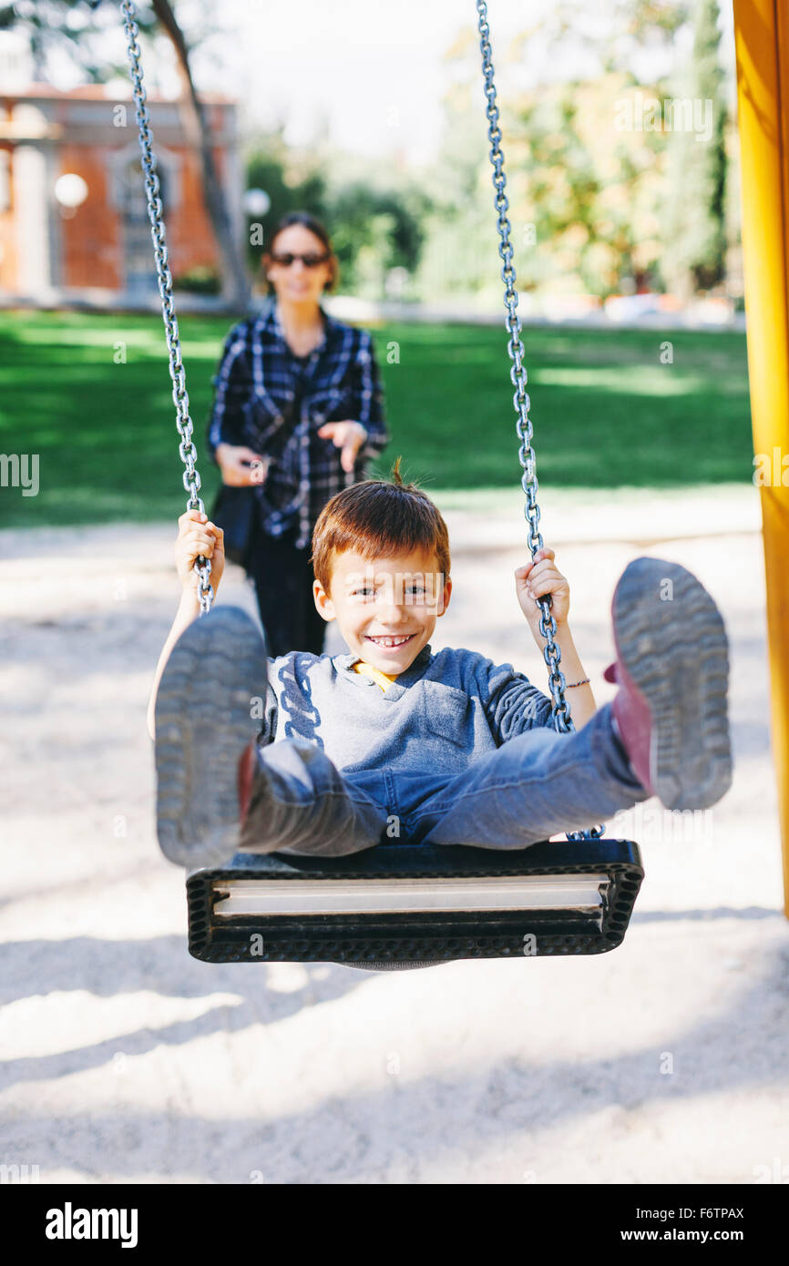 Happy boy on a swing at the playground Stock Photo - Alamy