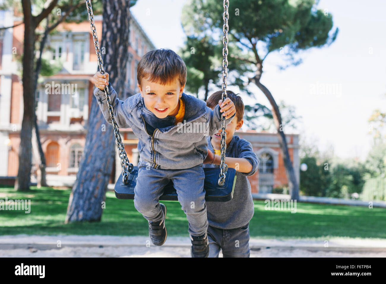 Brother pushing toddler on swing hi-res stock photography and images ...