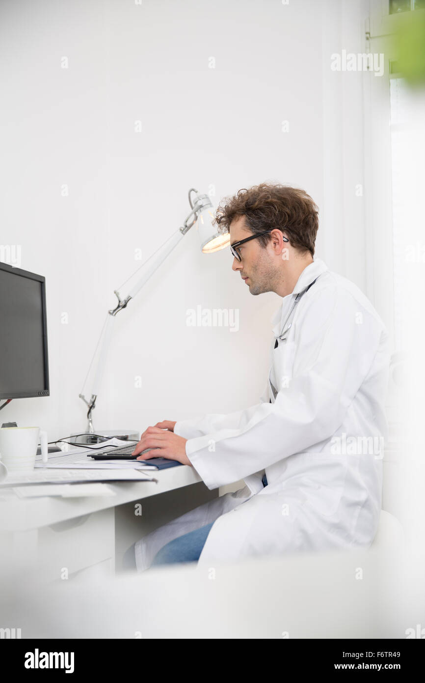 Doctor sitting at desk working on computer Stock Photo - Alamy