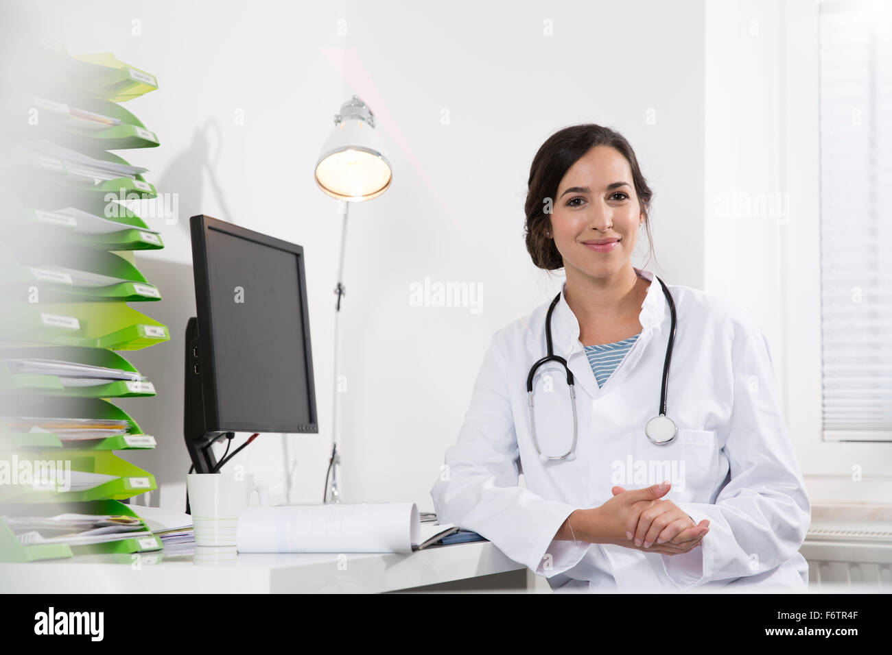 Portrait of smiling doctor sitting at desk Stock Photo - Alamy