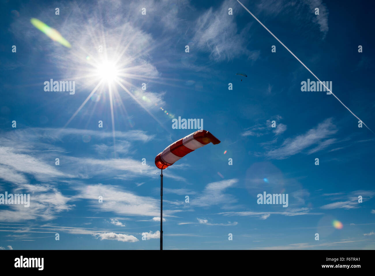 Windsock against the sun with paraglider in background Stock Photo - Alamy