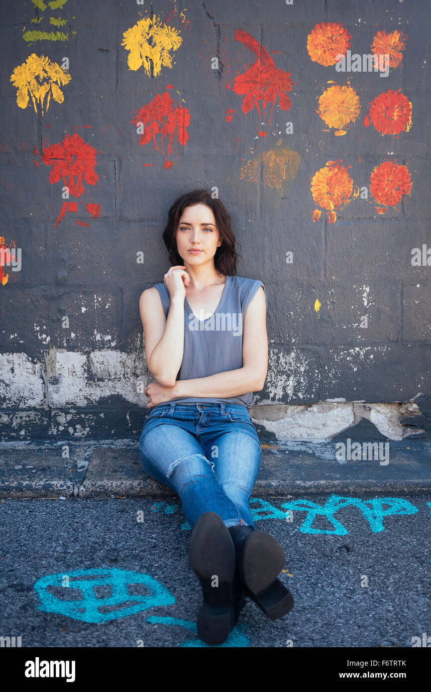USA, New York City, portrait of young woman sitting on the ground ...