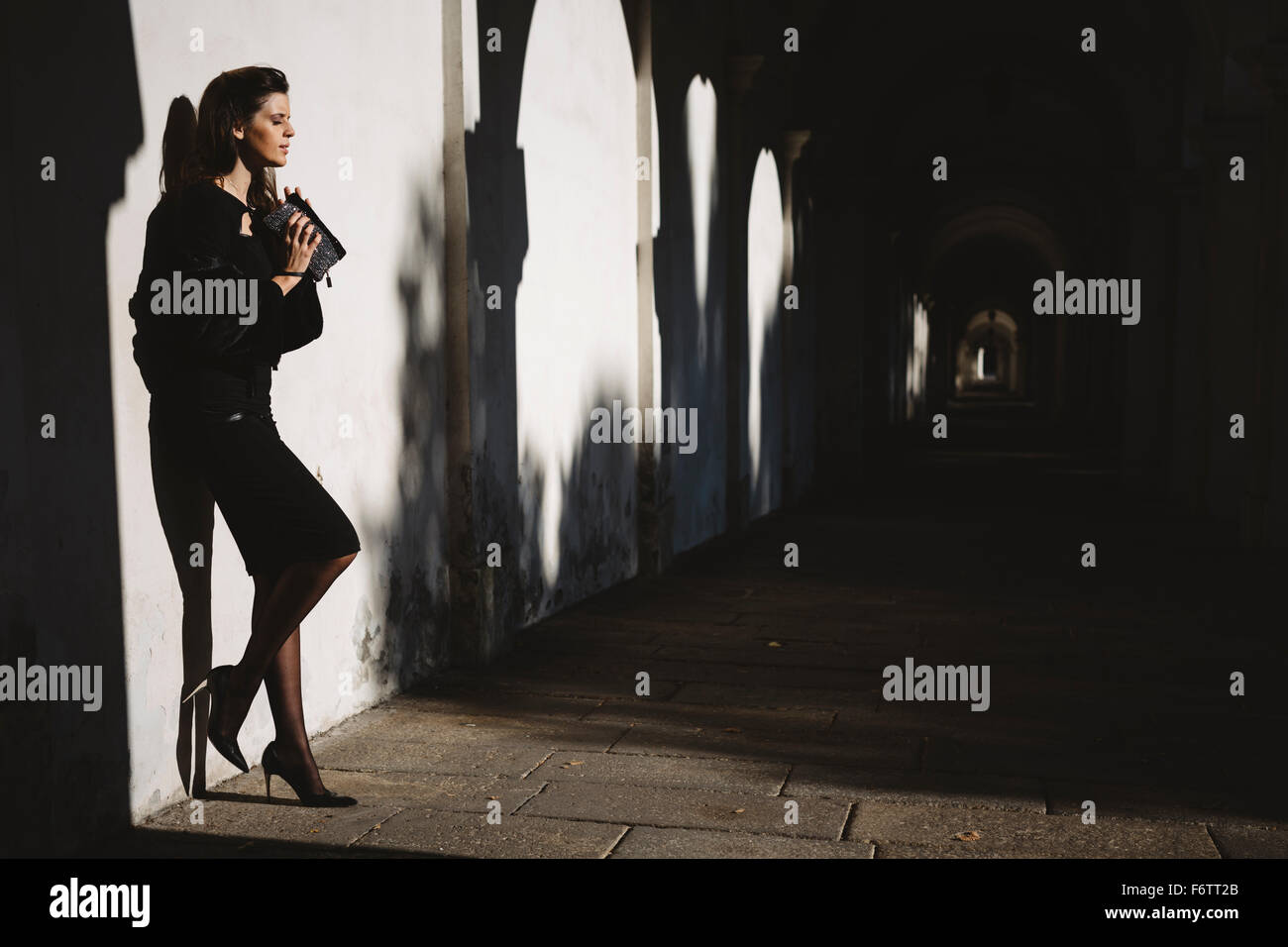 Young woman standing against a wall in an arcade Stock Photo - Alamy