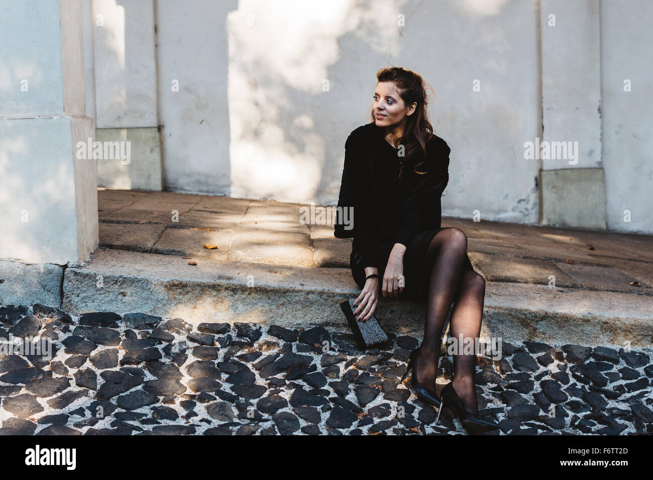 Fashionable young woman sitting on the ground Stock Photo - Alamy