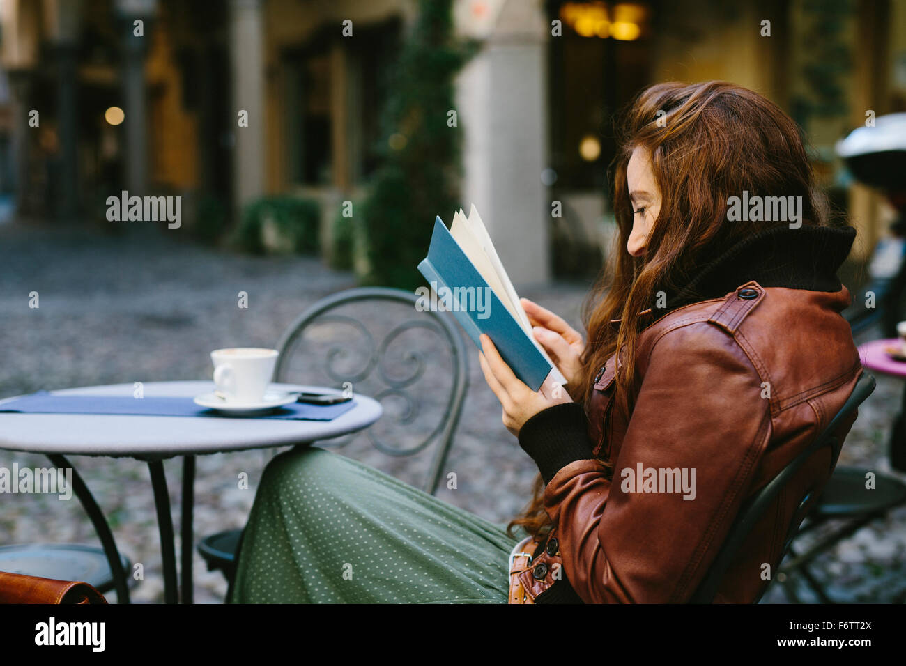 Woman reading a book outdoors in a little bar Stock Photo - Alamy