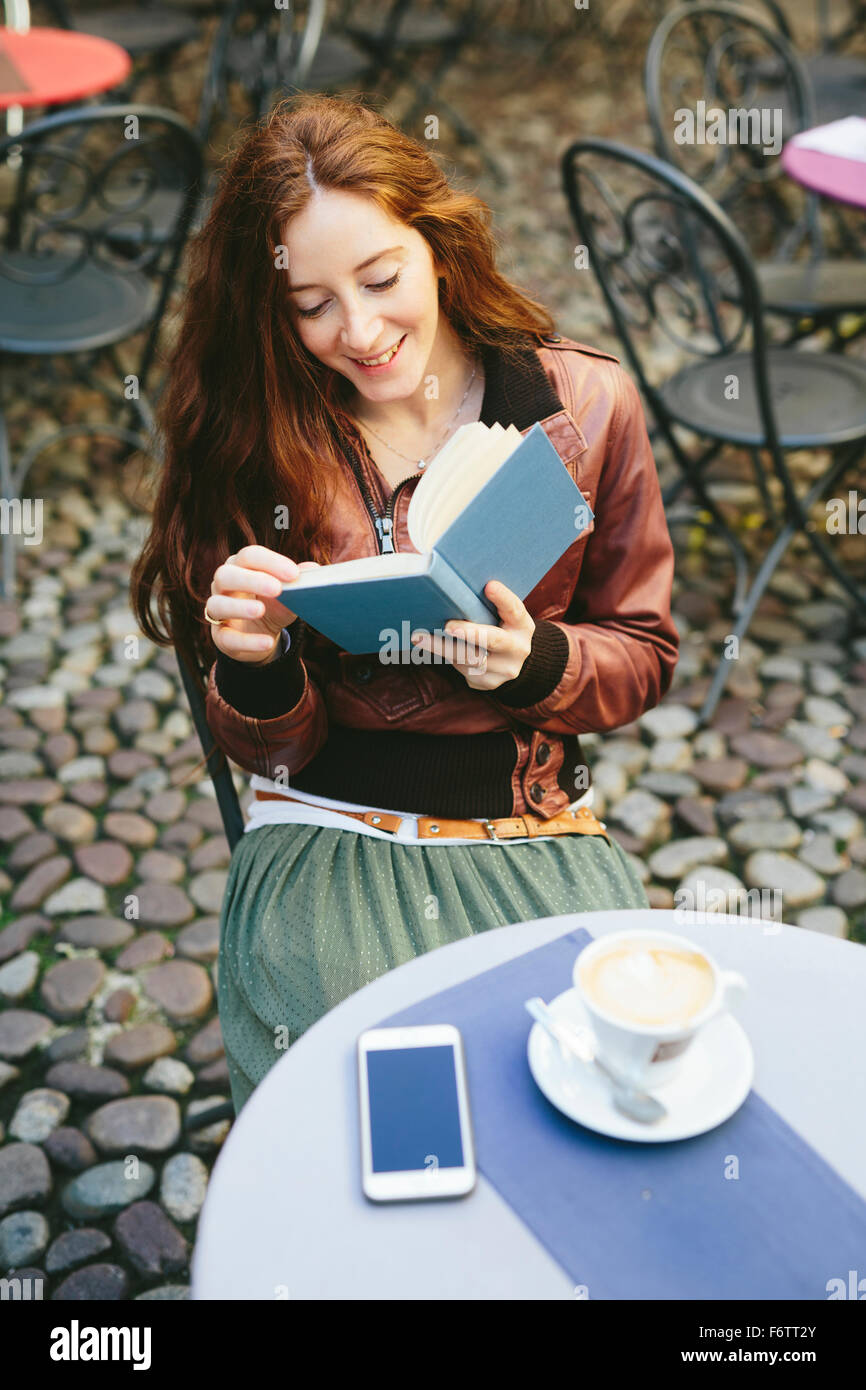 Woman reading a book outdoors in a little bar Stock Photo - Alamy