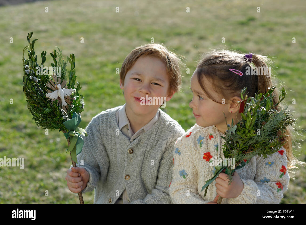 Germany, Upper Bavaria, little boy and girl with Palmbusch on a meadow ...