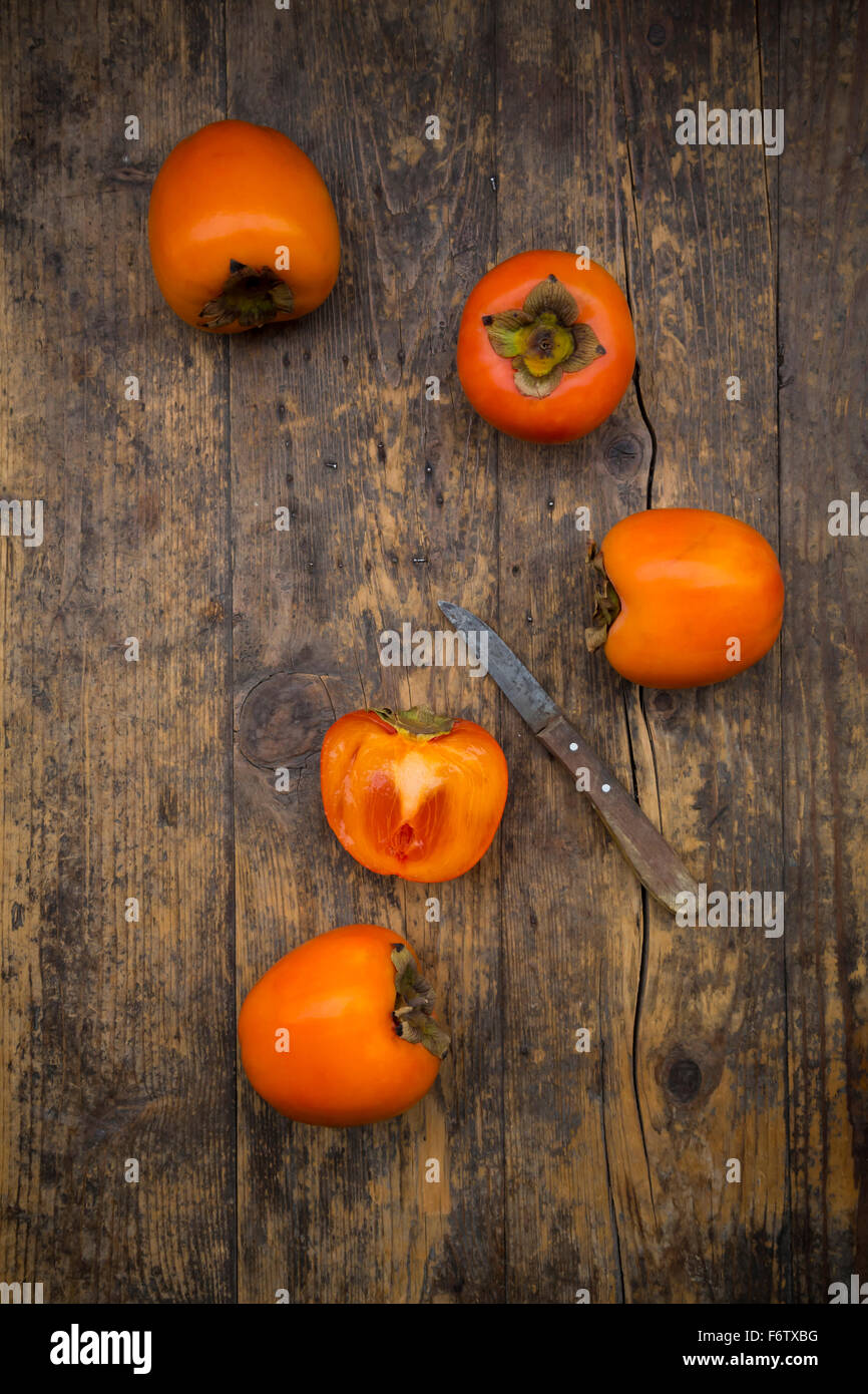 Whole and sliced kaki persimmons and a kitchen knife on wood Stock ...
