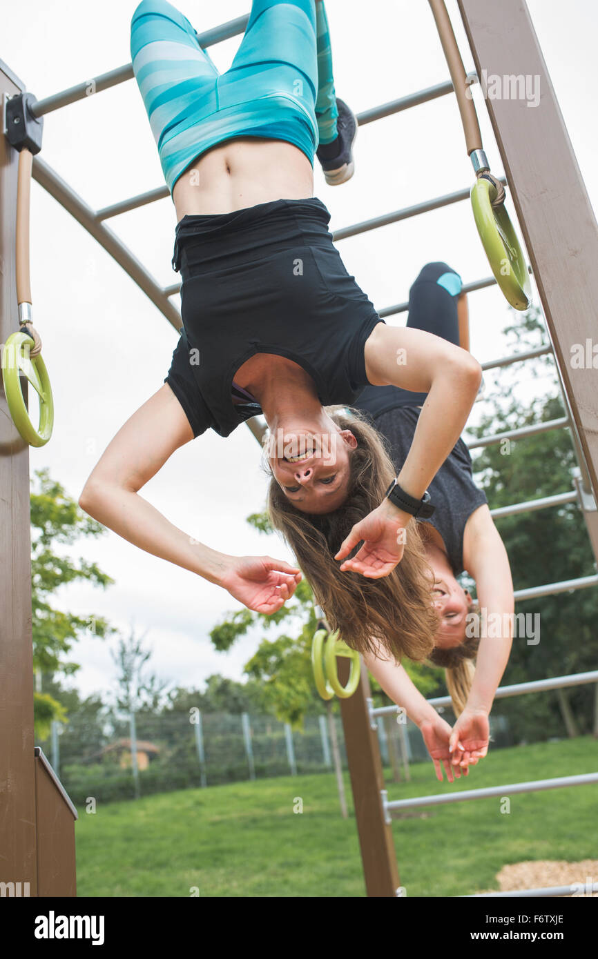 Two women having fun hanging in jungle gym Stock Photo - Alamy