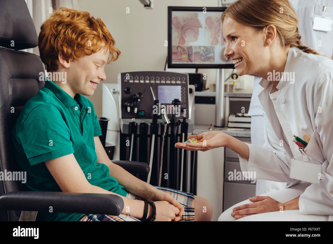 Female doctor giving child patient candy after successful screening in ...