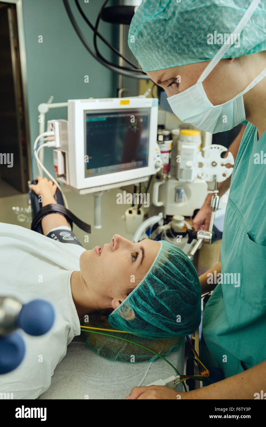 Female operating nurse talking to patient on table in operating room ...