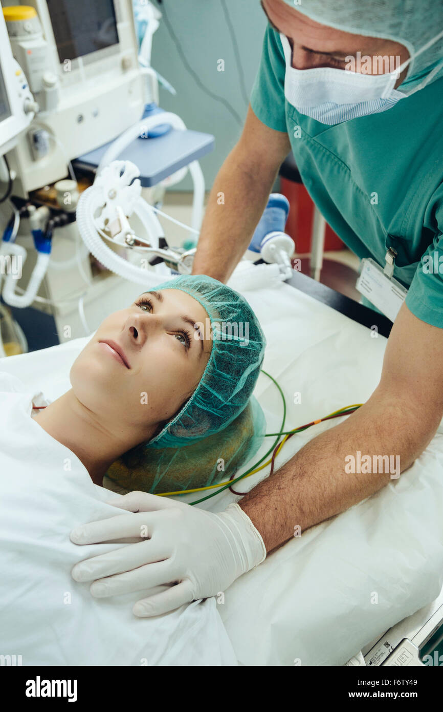 Operating nurse soothing patient on table in operating room Stock Photo ...