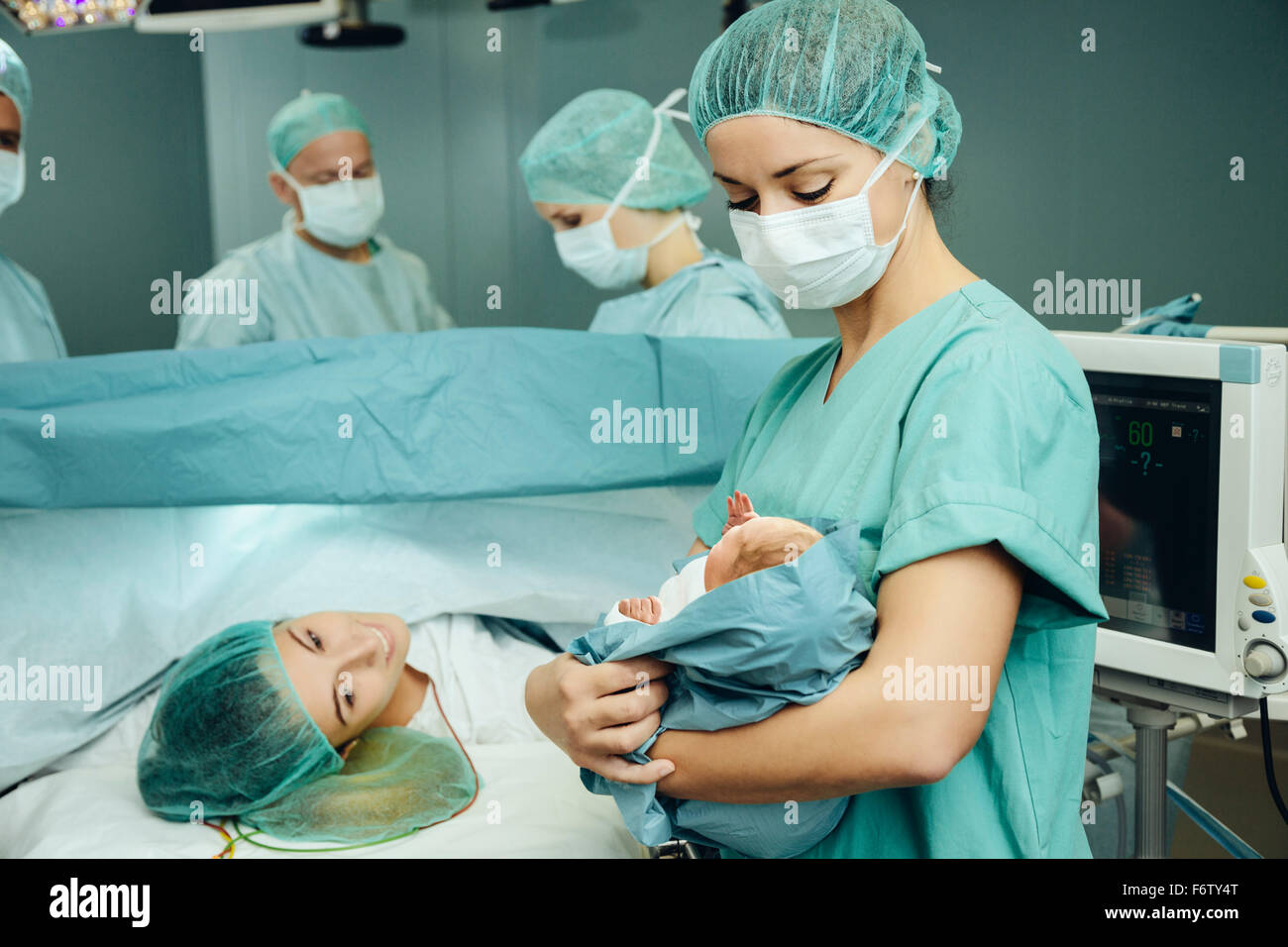 Operating room nurse showing newborn to mother Stock Photo - Alamy
