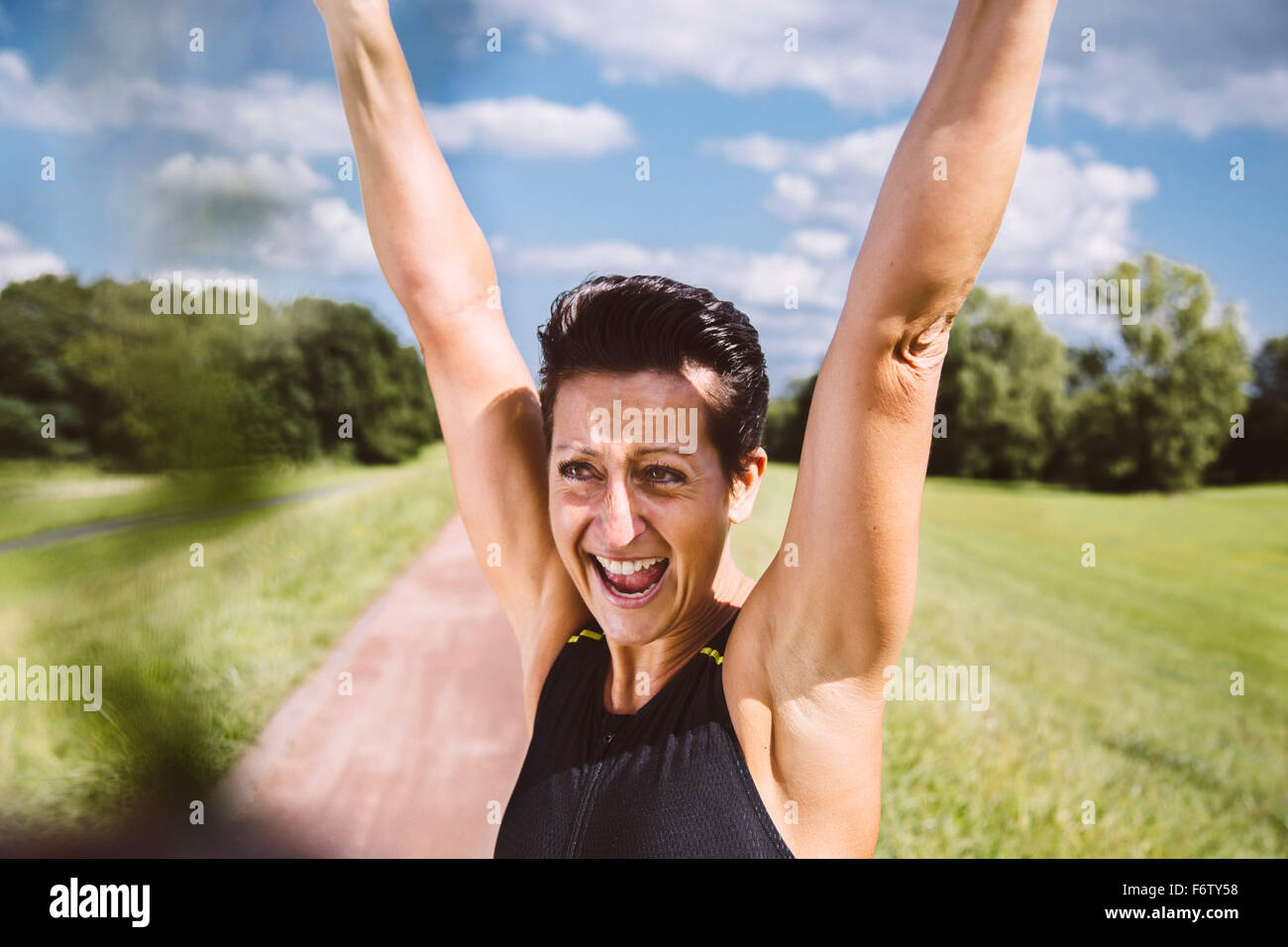 Female triathlete cheering with arms up Stock Photo - Alamy