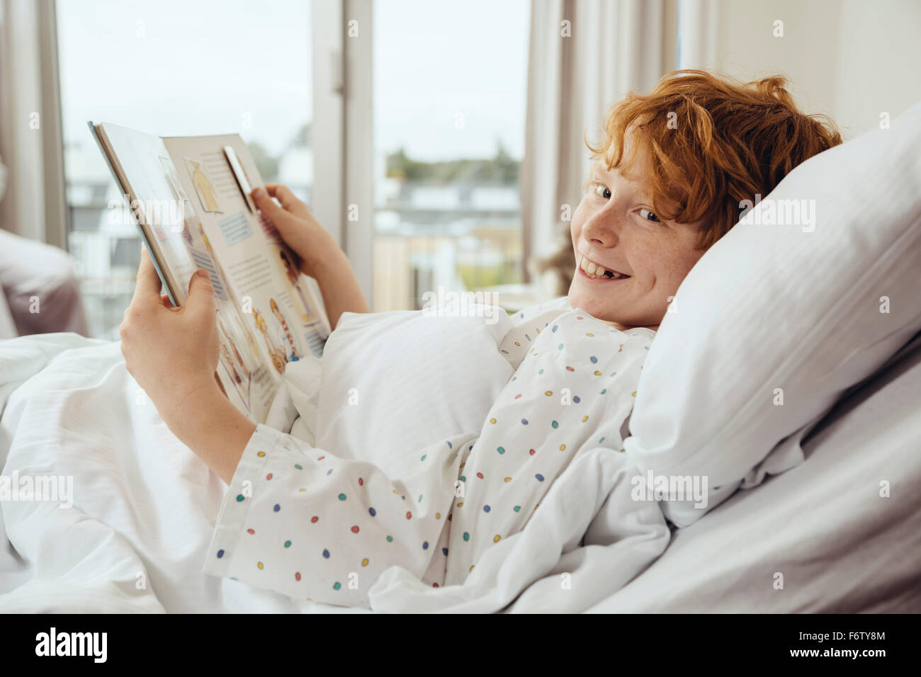 Sick boy reading book lying in hospital bed Stock Photo - Alamy