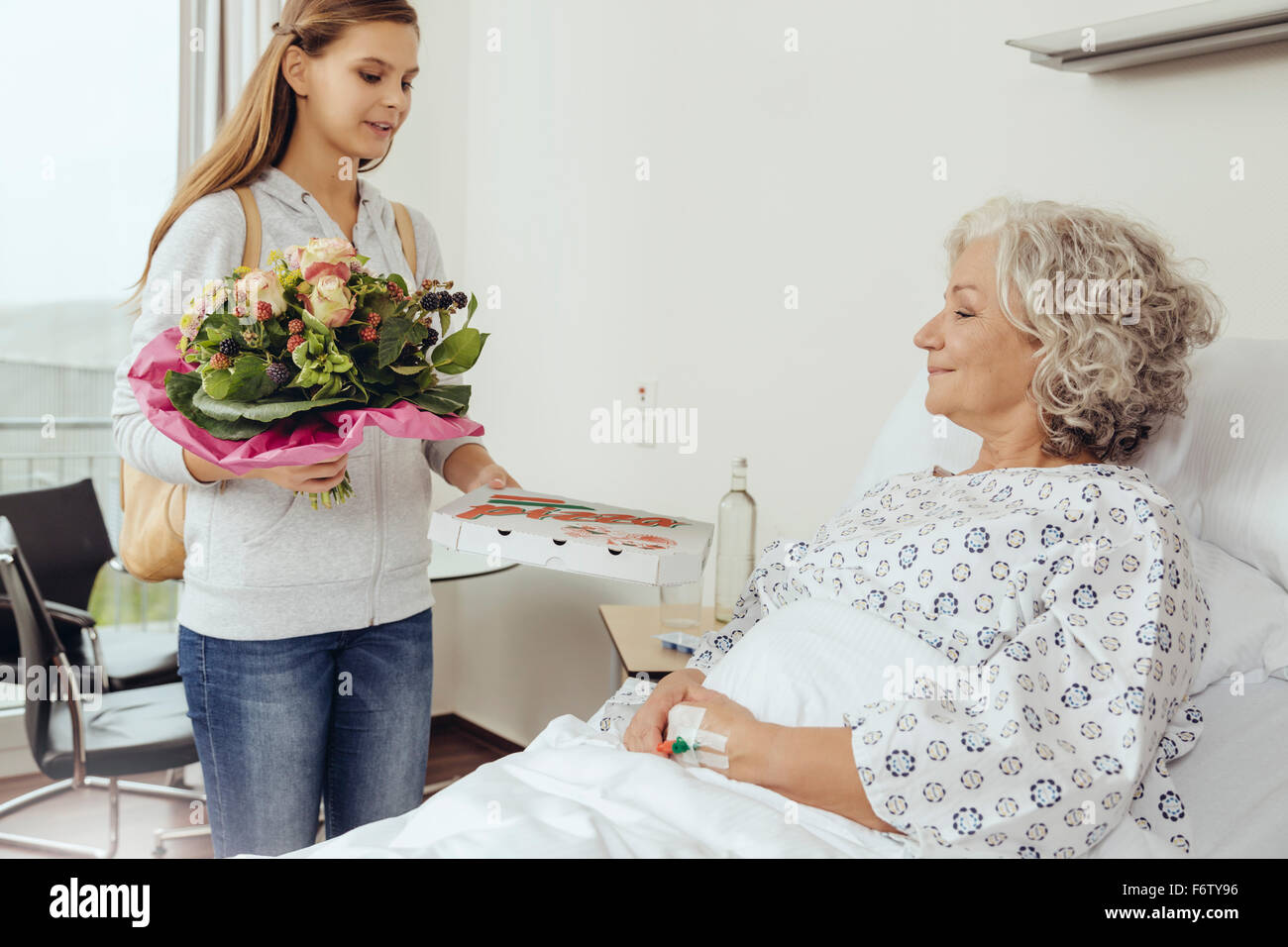 Granddaughter visiting grandmother in hospital, bringing bunch of ...