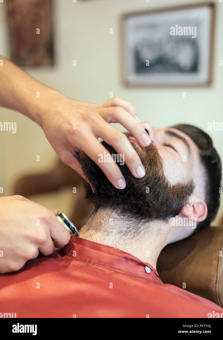 Barber shaving beard of a customer Stock Photo - Alamy