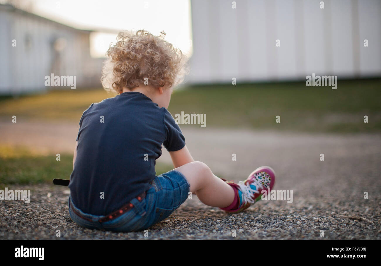 Little girl sitting on gravel path Stock Photo - Alamy