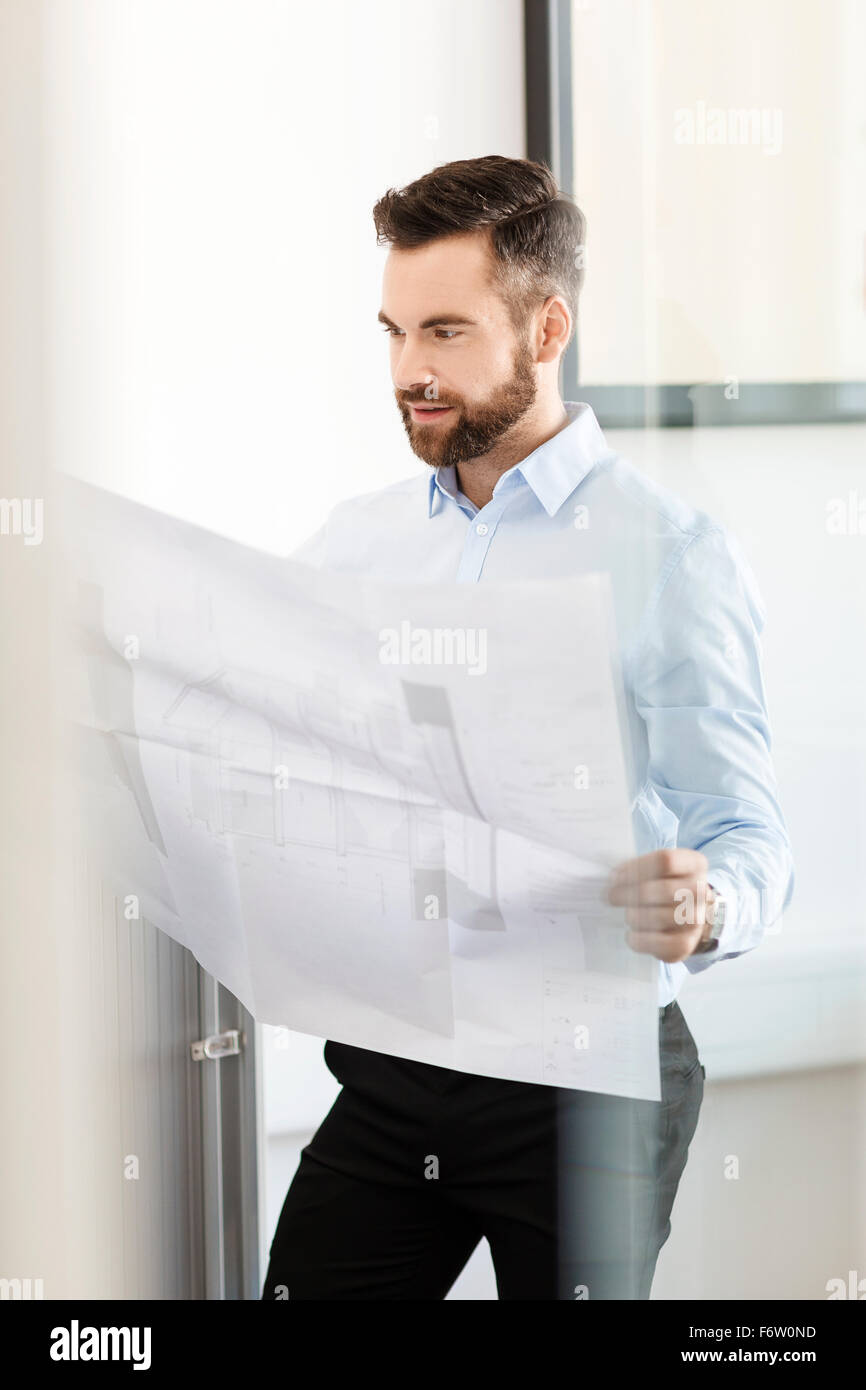 Man in office looking at construction plan Stock Photo - Alamy