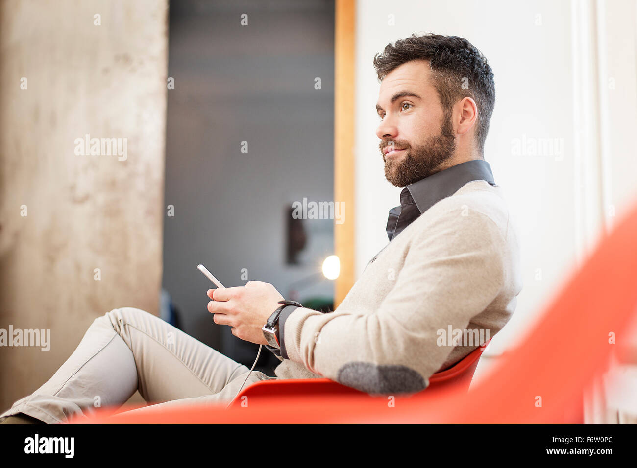 Man sitting in chair holding cell phone Stock Photo - Alamy