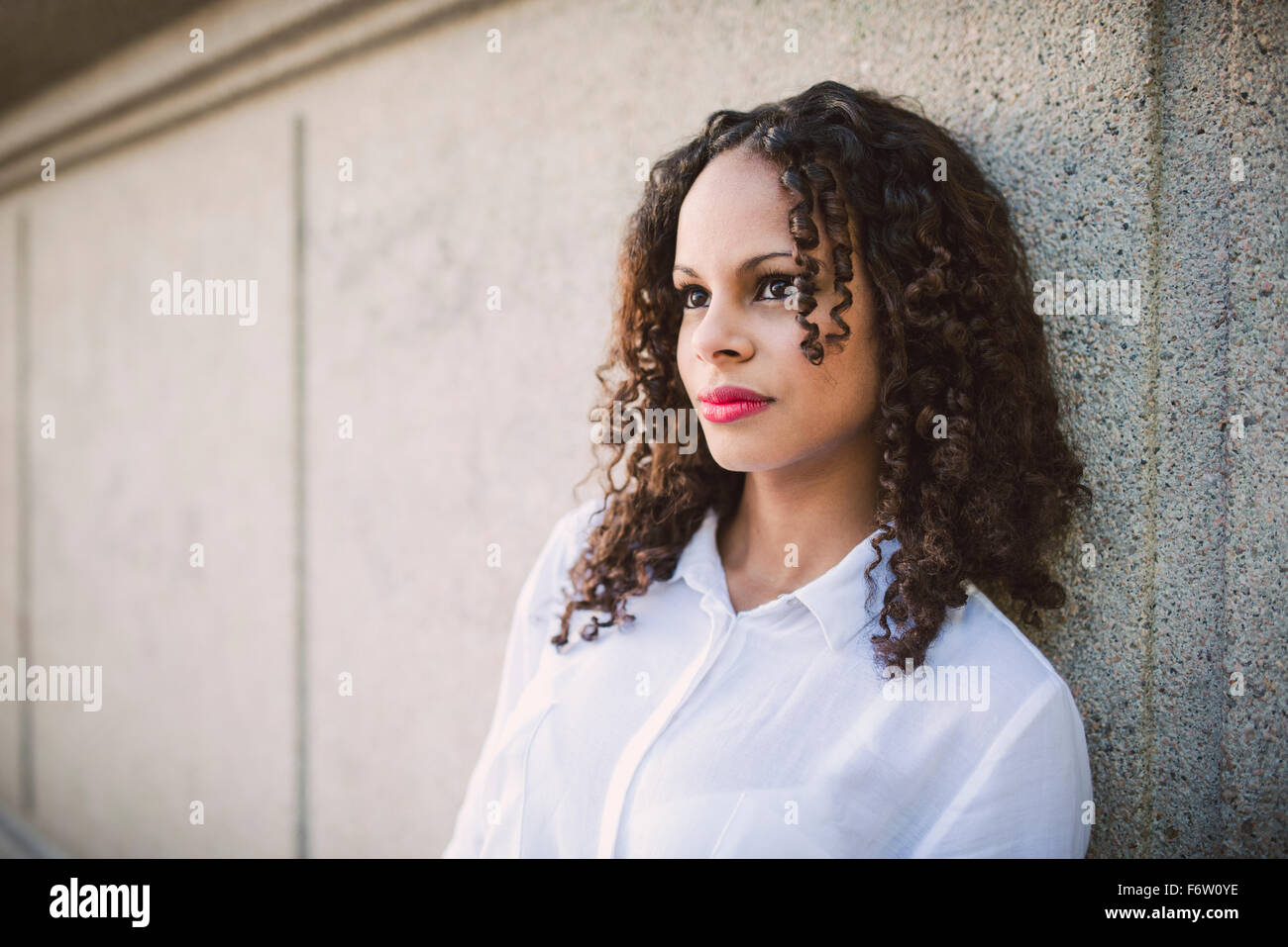 Portrait of young woman with brown ringlets and red lips leaning ...