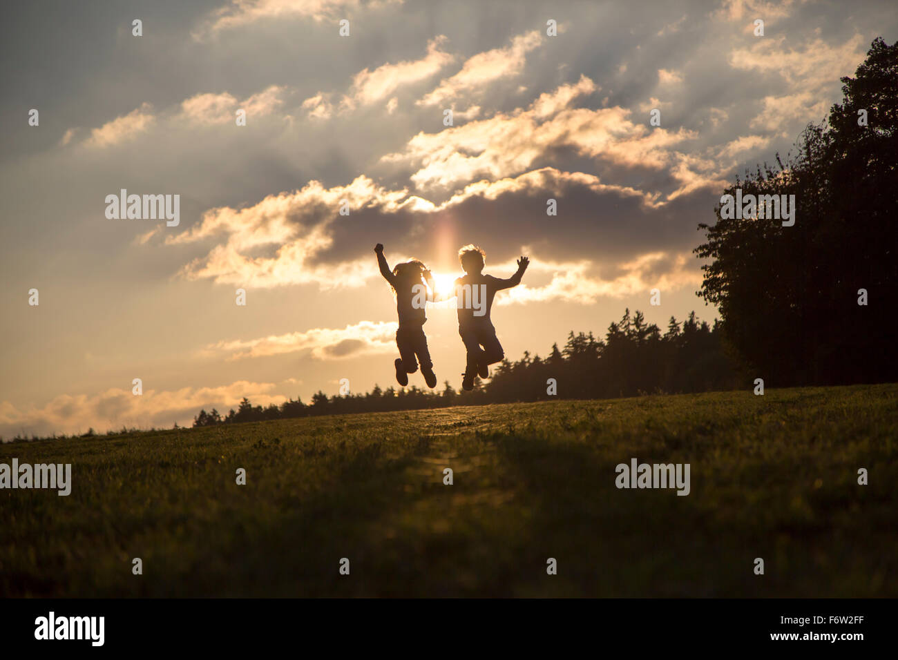 Silhouettes two children jumping side hi-res stock photography and ...