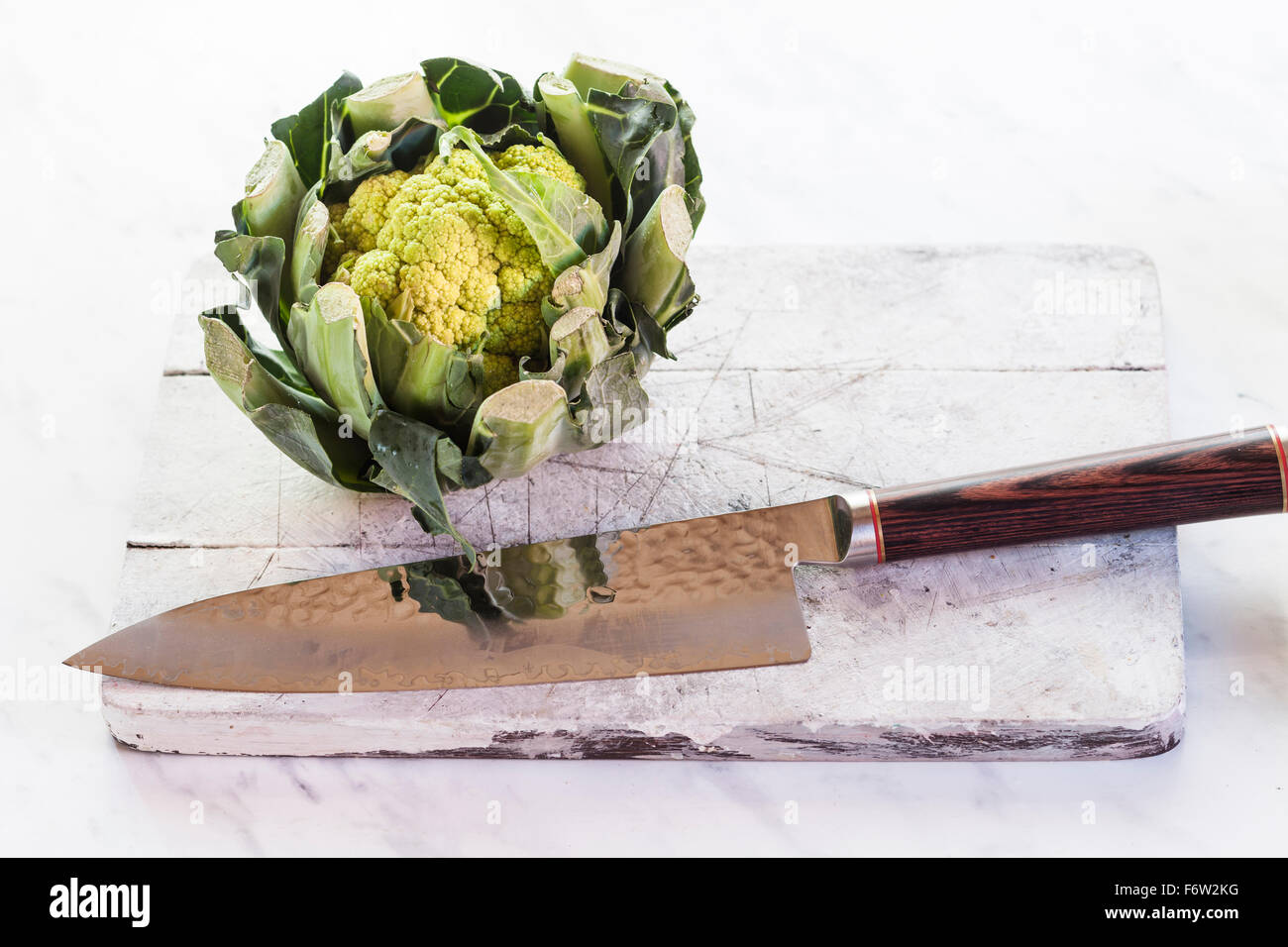 Green cauliflower and knife on chopping board Stock Photo - Alamy