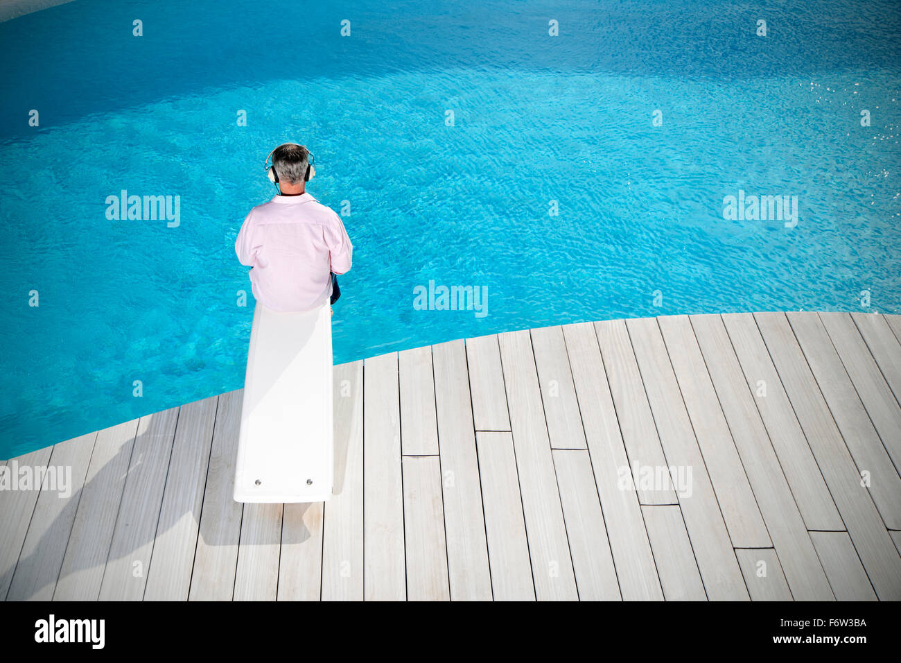 Spain, Mallorca, back view of man sitting on springboard of a pool ...