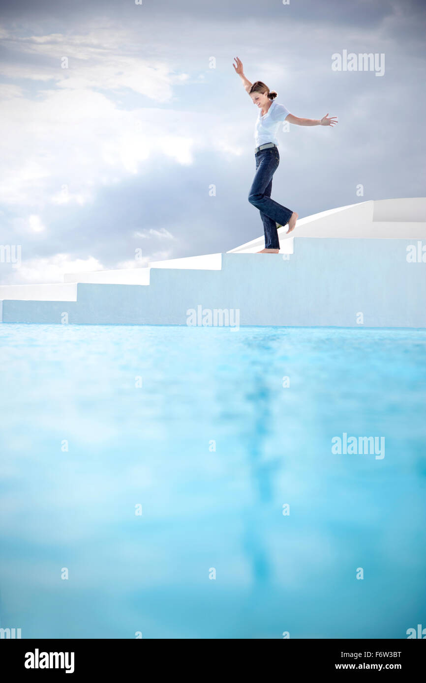Spain, Mallorca, woman balancing on stairs with beside a swimming pool ...