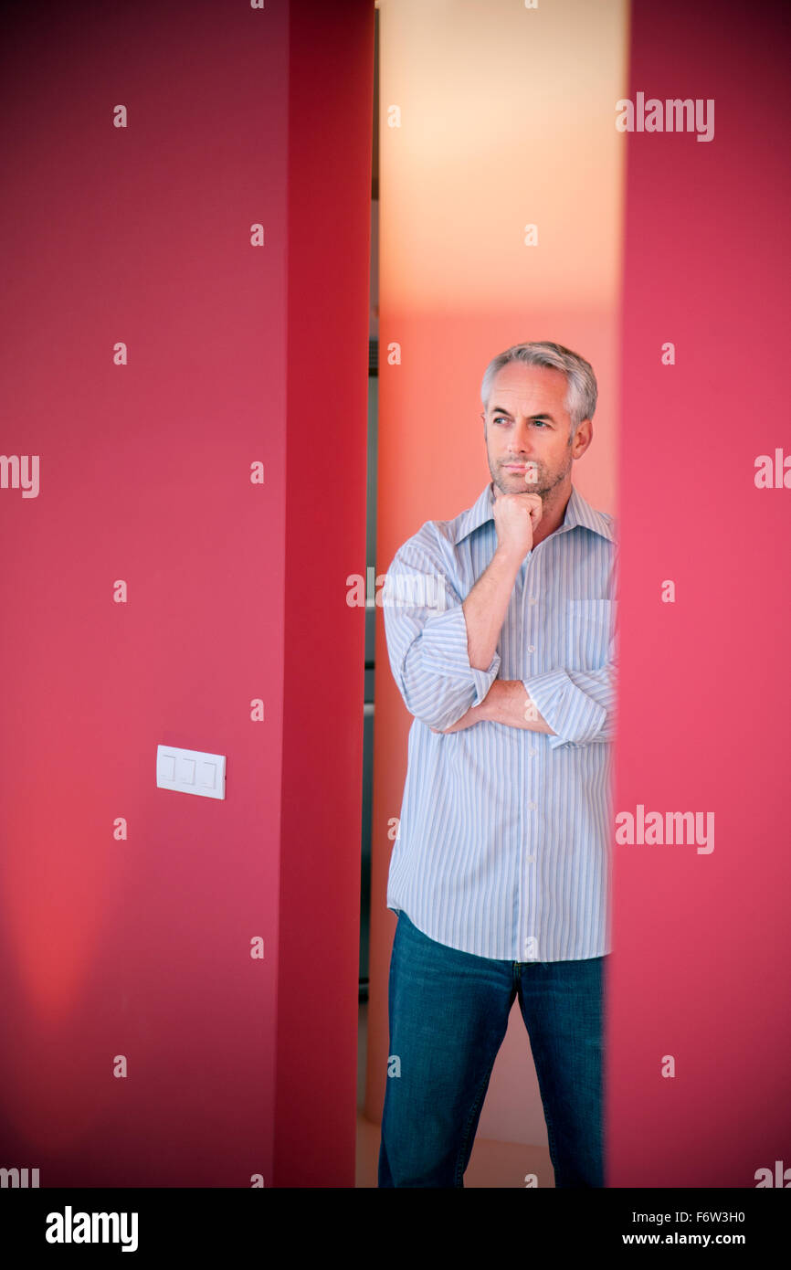Portrait of pensive man standing between two red walls Stock Photo - Alamy