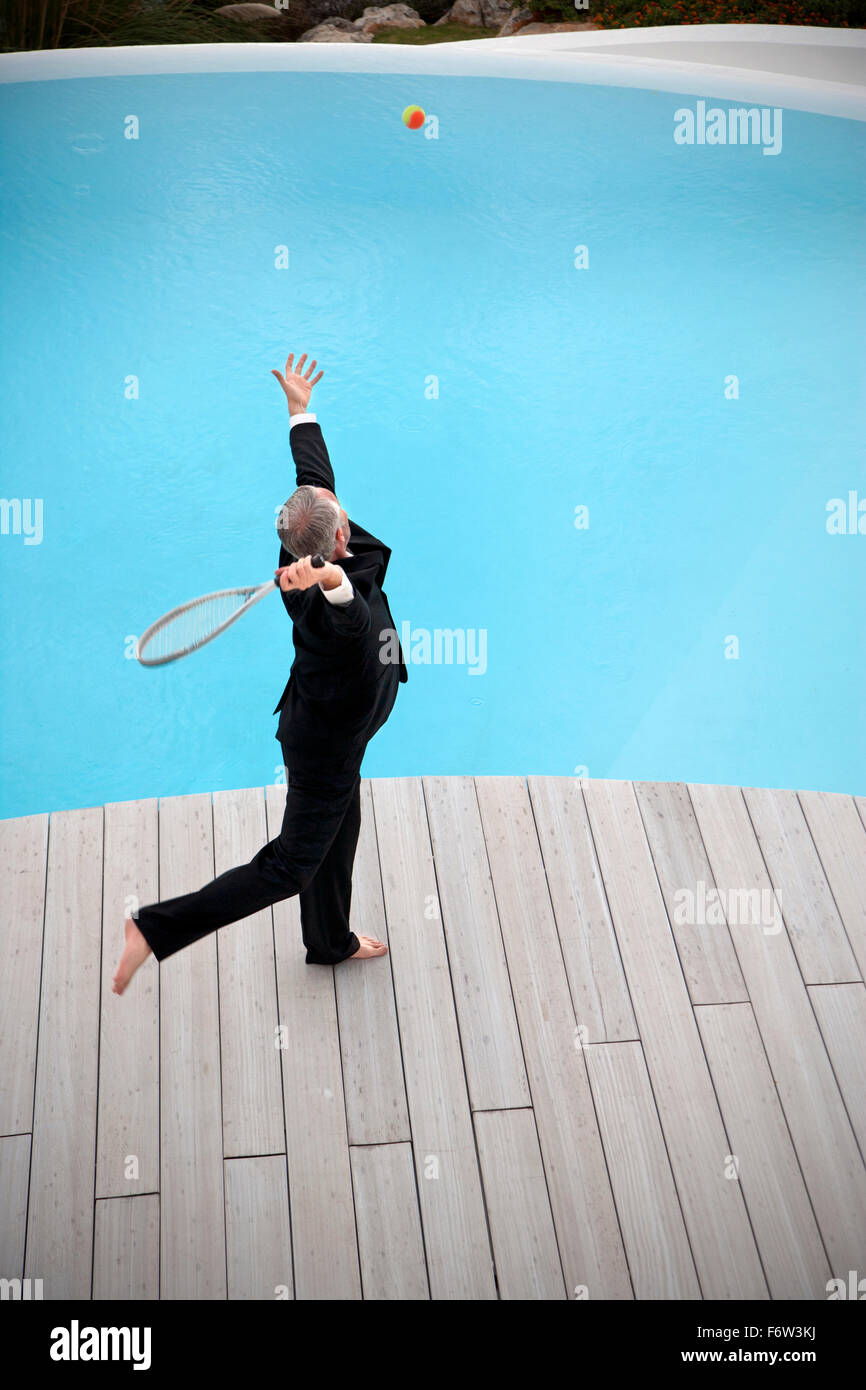 Barefoot businessman wearing black suit playing with ball and racket in ...