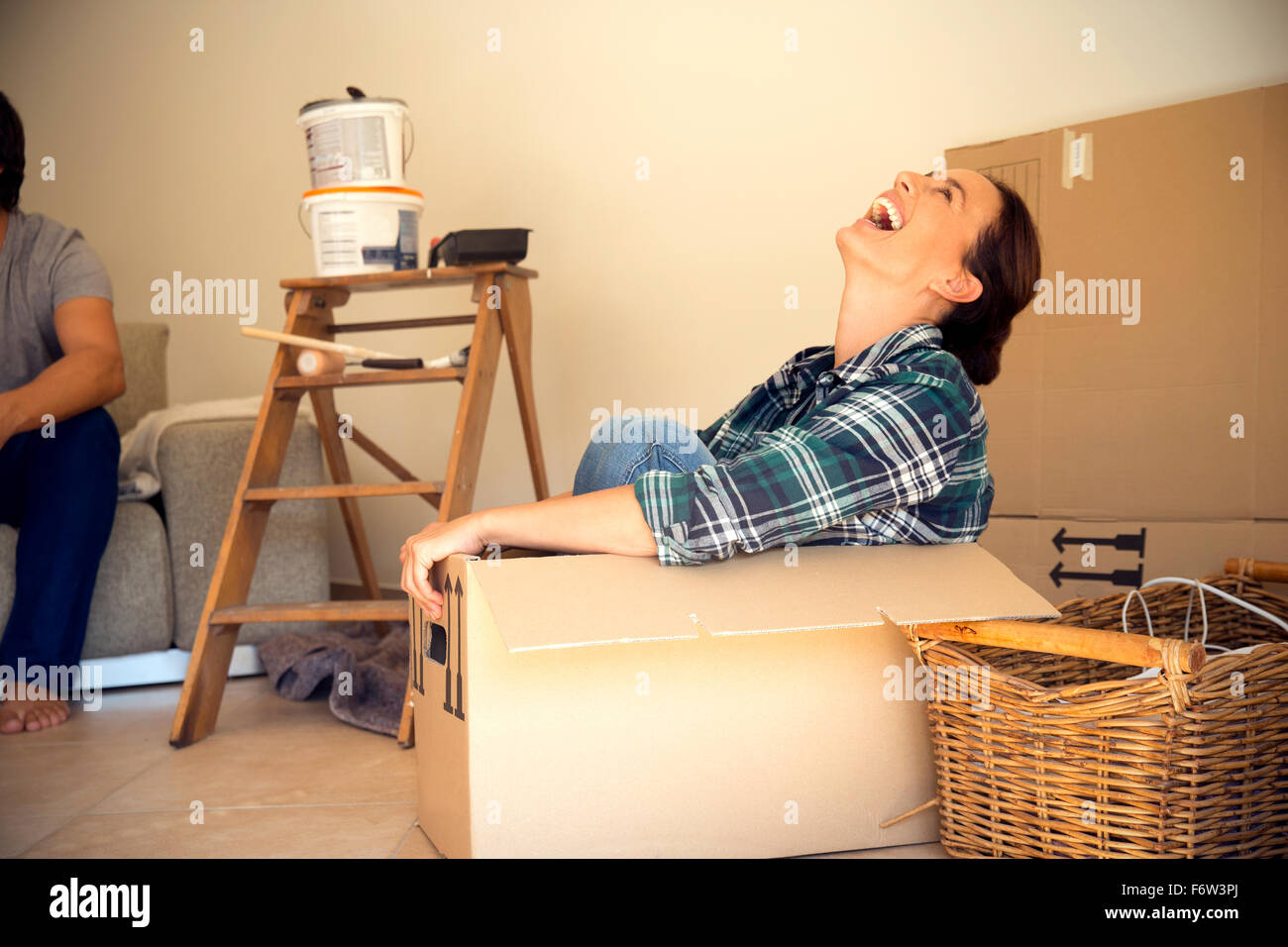 Laughing woman in cardboard box with man in background Stock Photo - Alamy