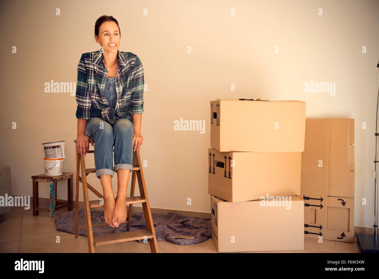 Smiling woman sitting on step ladder beside cardboard boxes Stock Photo ...