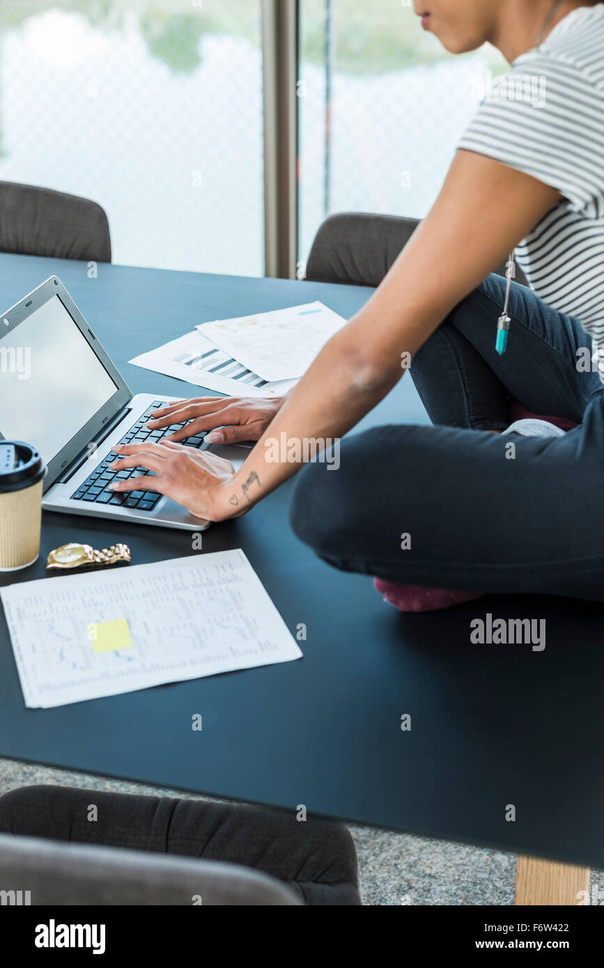 Young woman sitting on conference table using laptop Stock Photo - Alamy