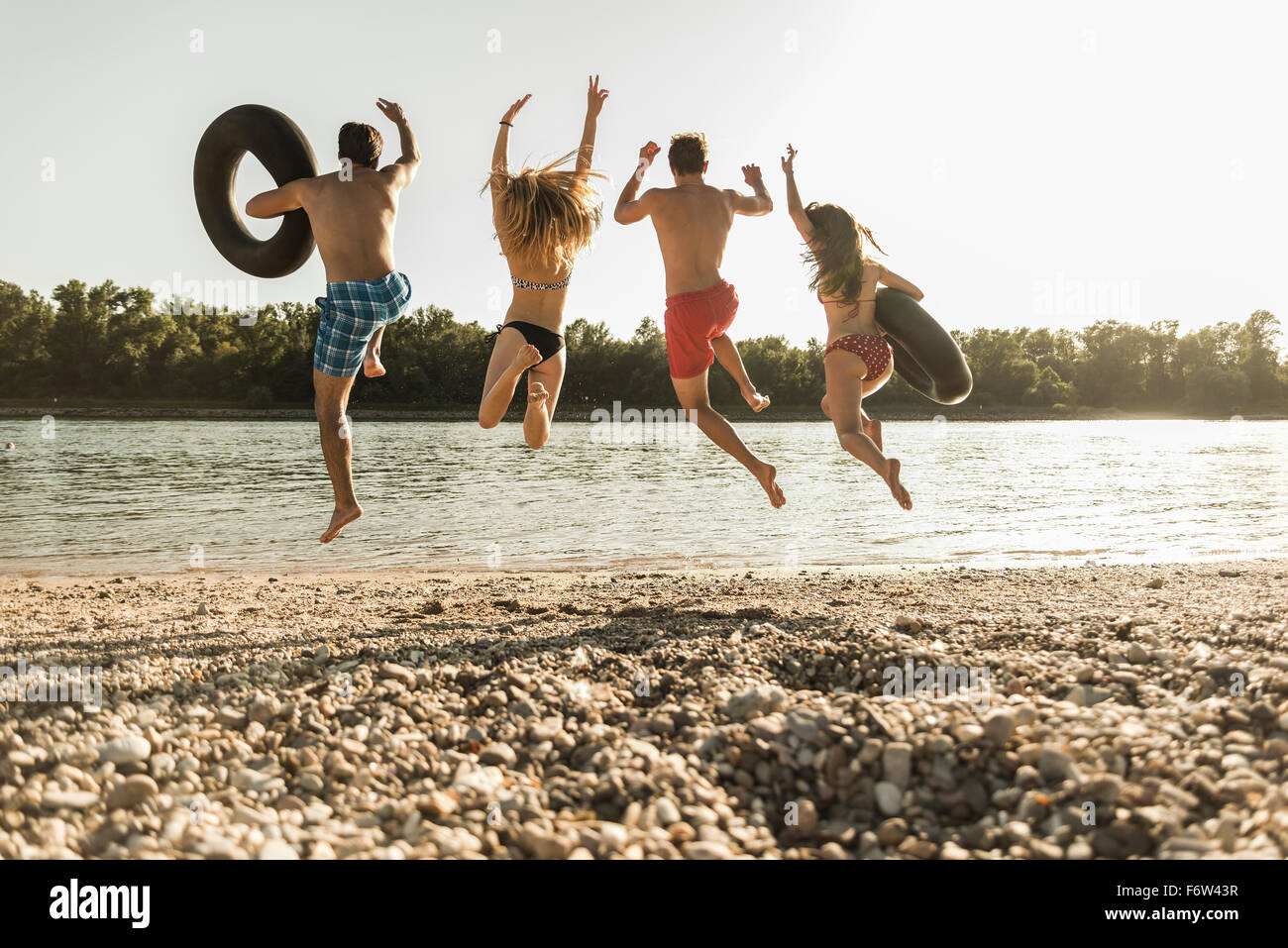Friends with inner tubes jumping into river Stock Photo - Alamy