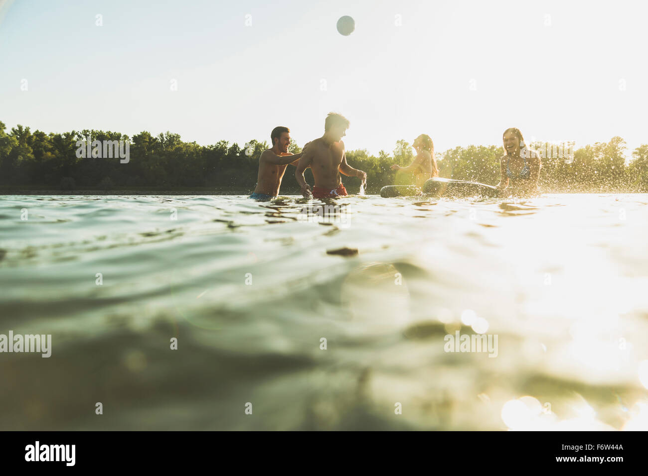 Happy friends with inner tubes and ball in water Stock Photo - Alamy